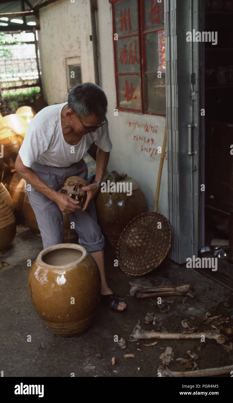 A Man removes bones from a earthenware earthenware jar and washes them ...