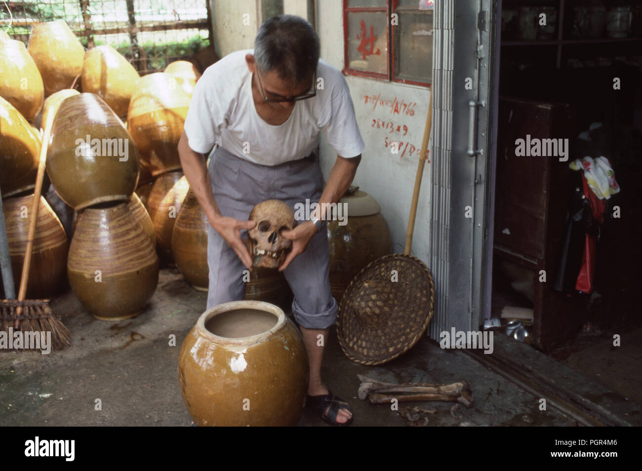 A Man removes bones from a earthenware earthenware jar and washes them ...