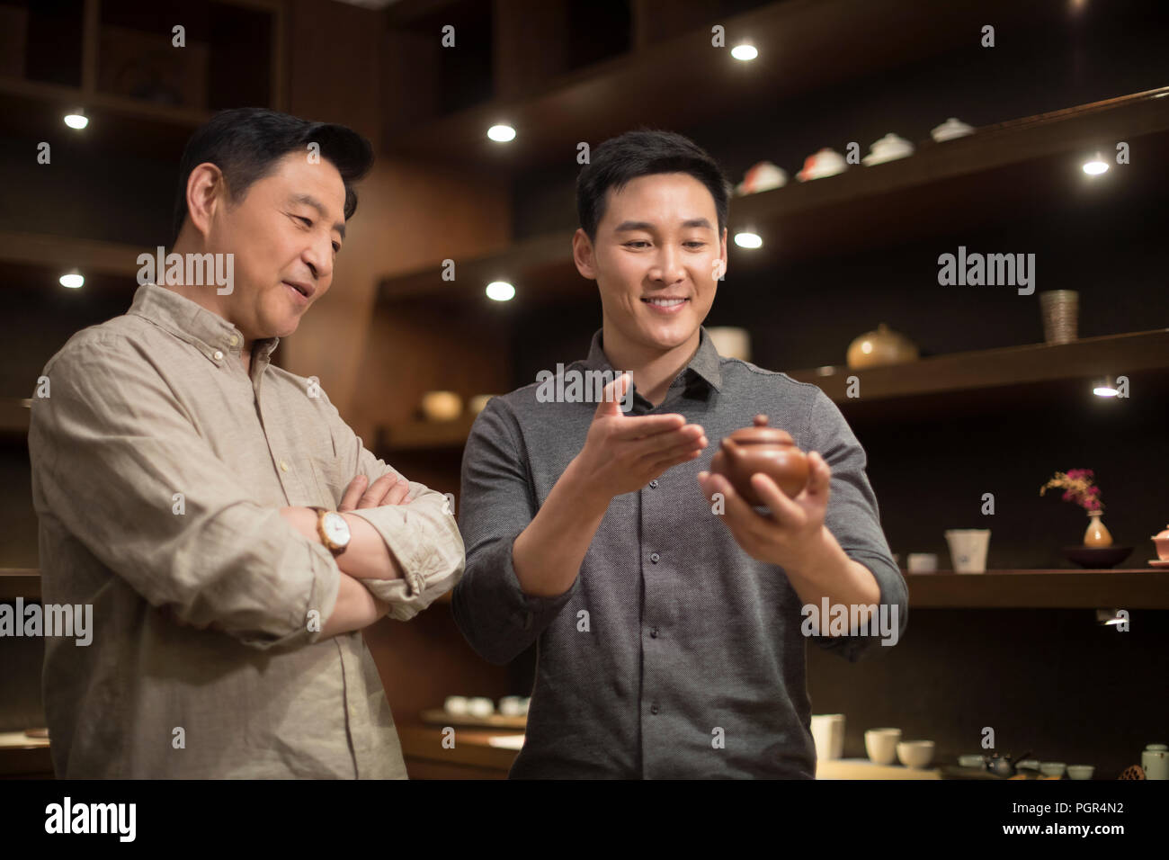 Mid adult man showing a teapot to customer Stock Photo - Alamy