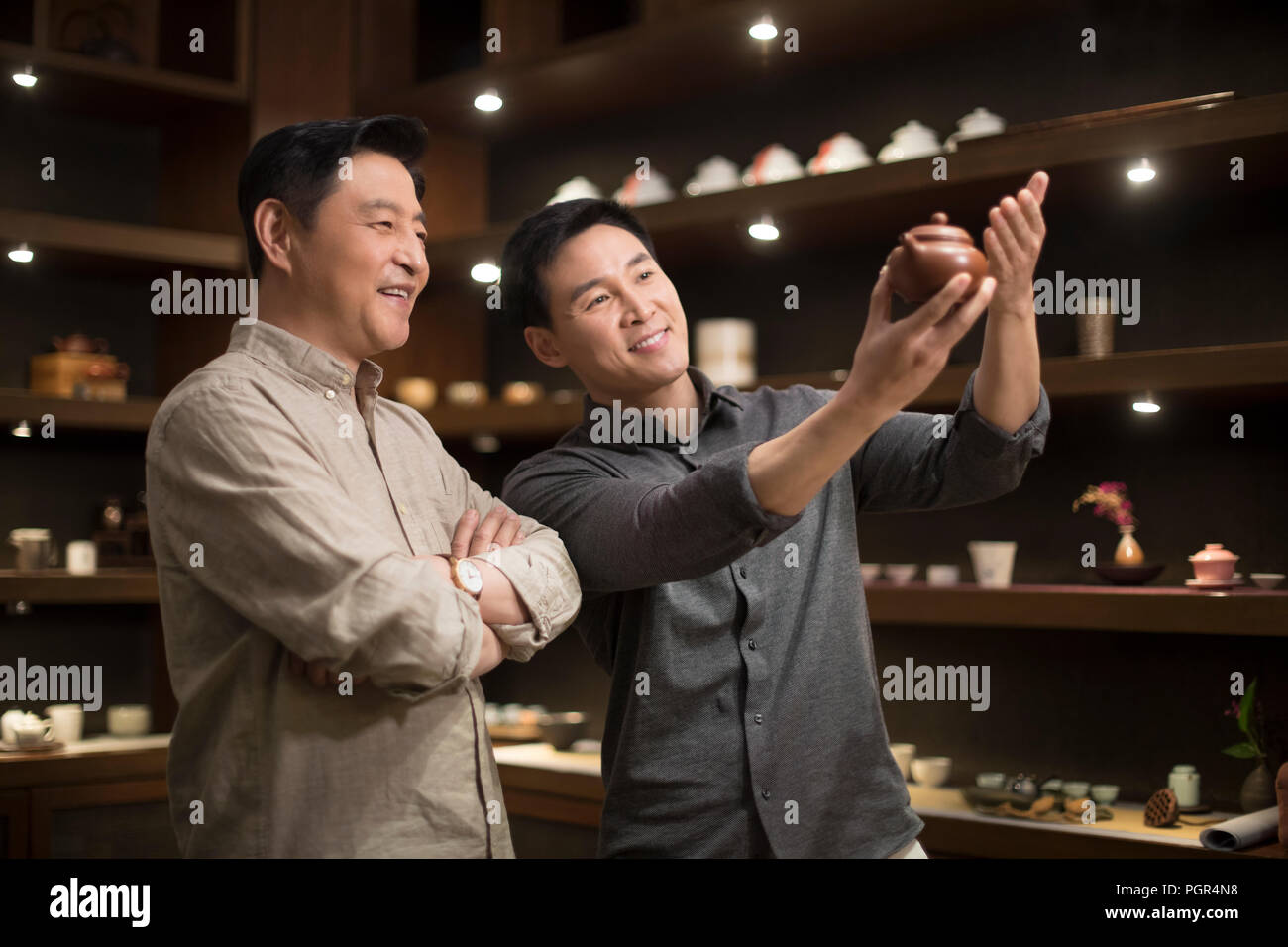 Mid adult man showing a teapot to customer Stock Photo - Alamy