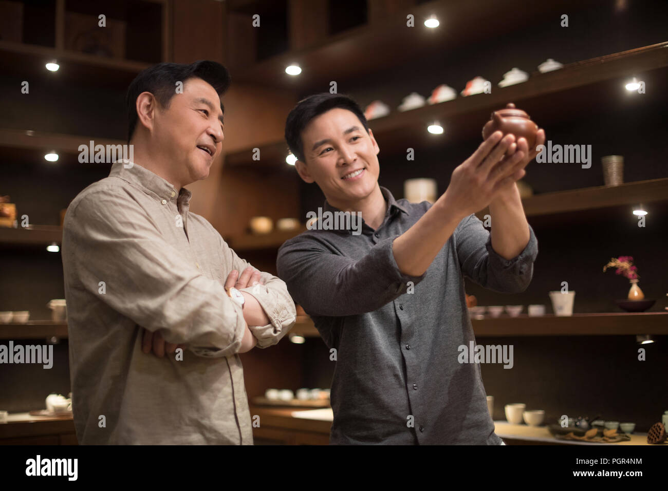 Mid adult man showing a teapot to customer Stock Photo - Alamy