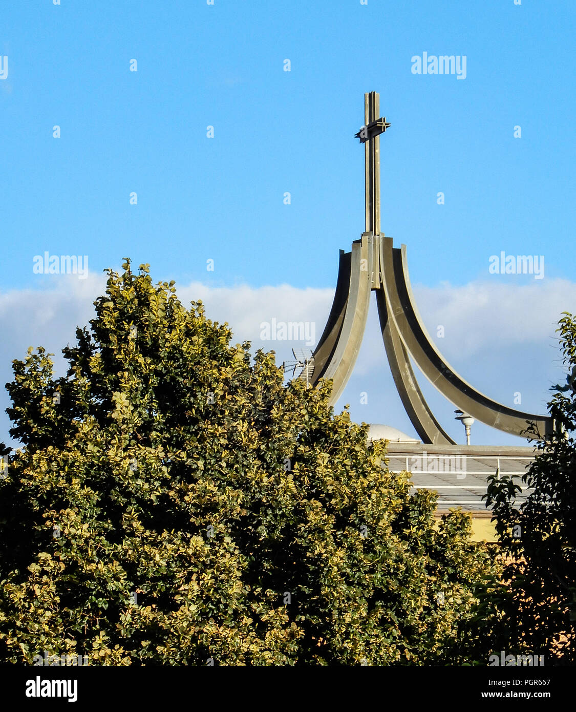 A modern steel church spire rises above the trees in Ostia Stock Photo ...