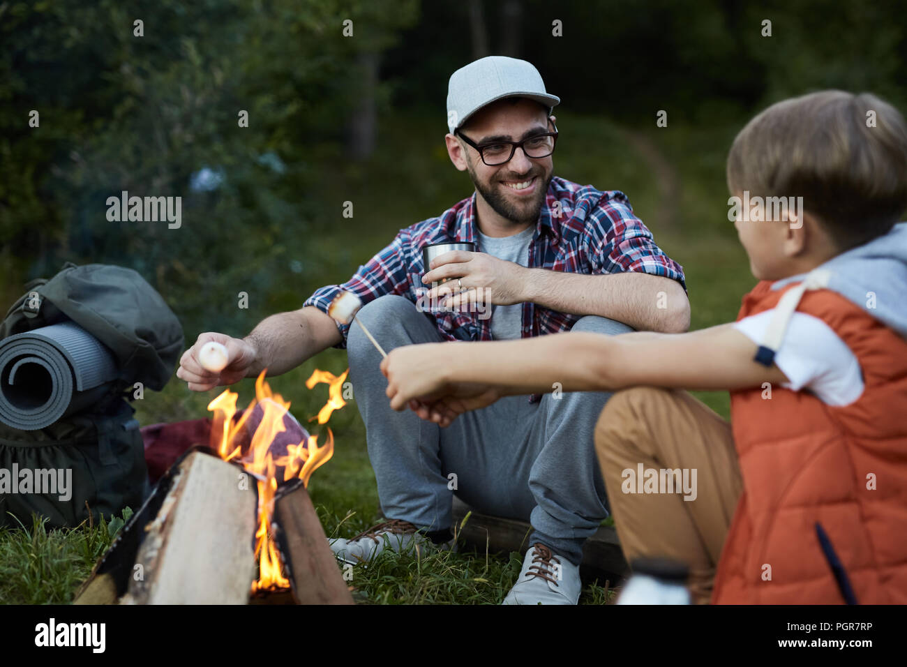 Dad and son are heated by the fire, eat marshmallows and drink hot tea ...