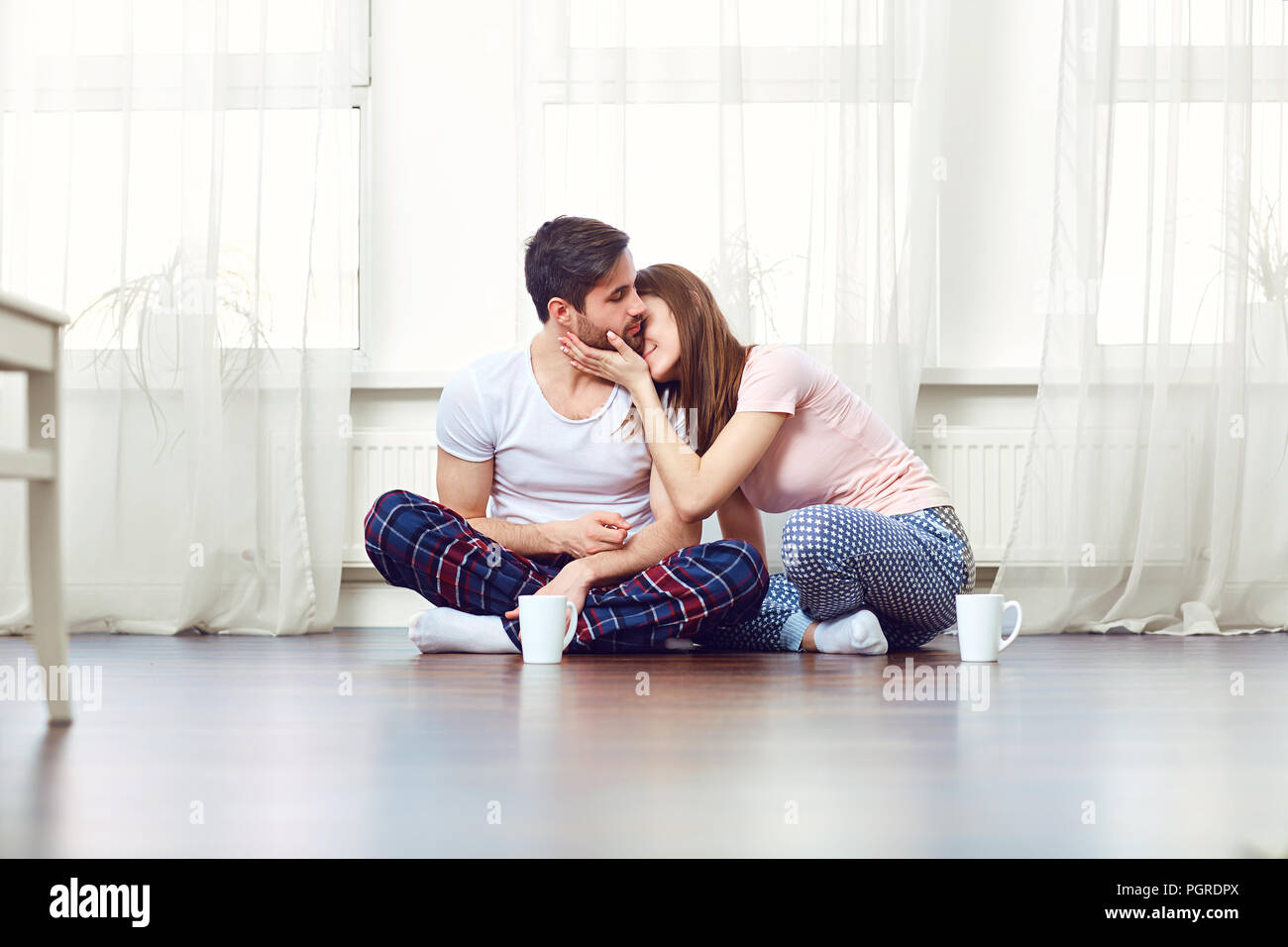 A loving couple hugging on the floor against the window Stock Photo - Alamy