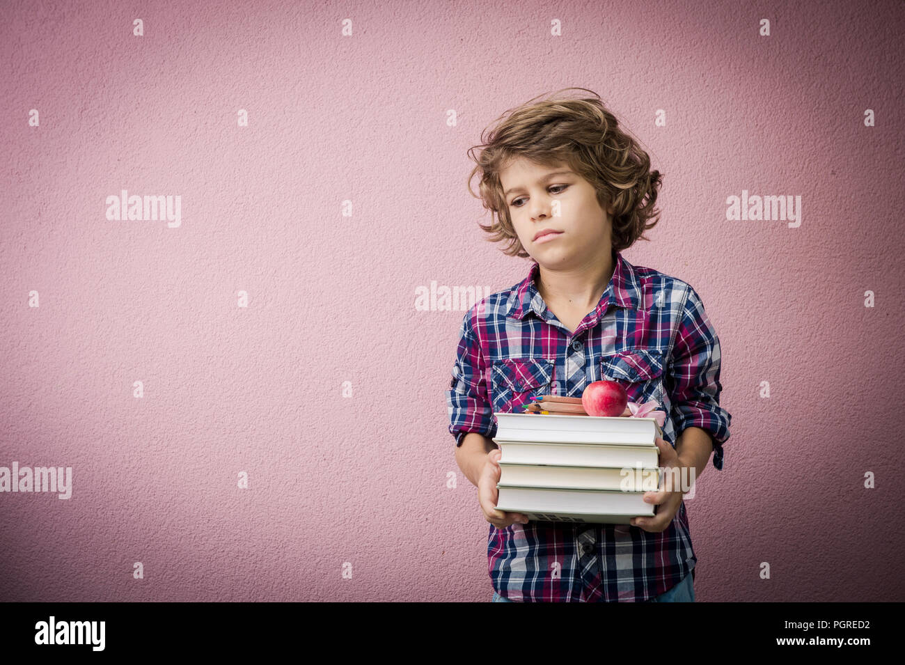 Little boy with stack of books frowning because he has to go back to ...