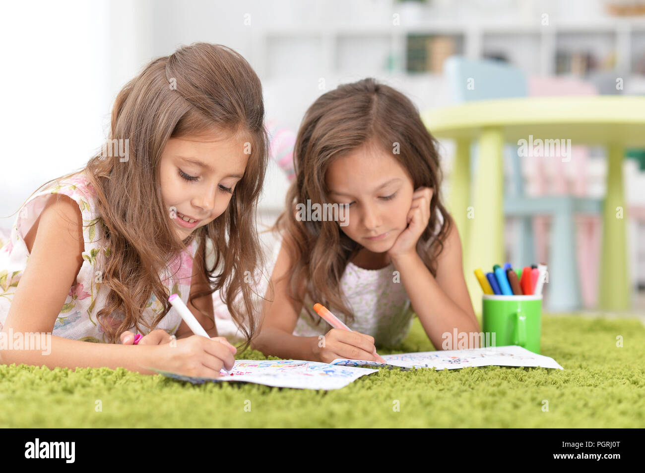 Portrait of a two cute little girls drawing together Stock Photo - Alamy