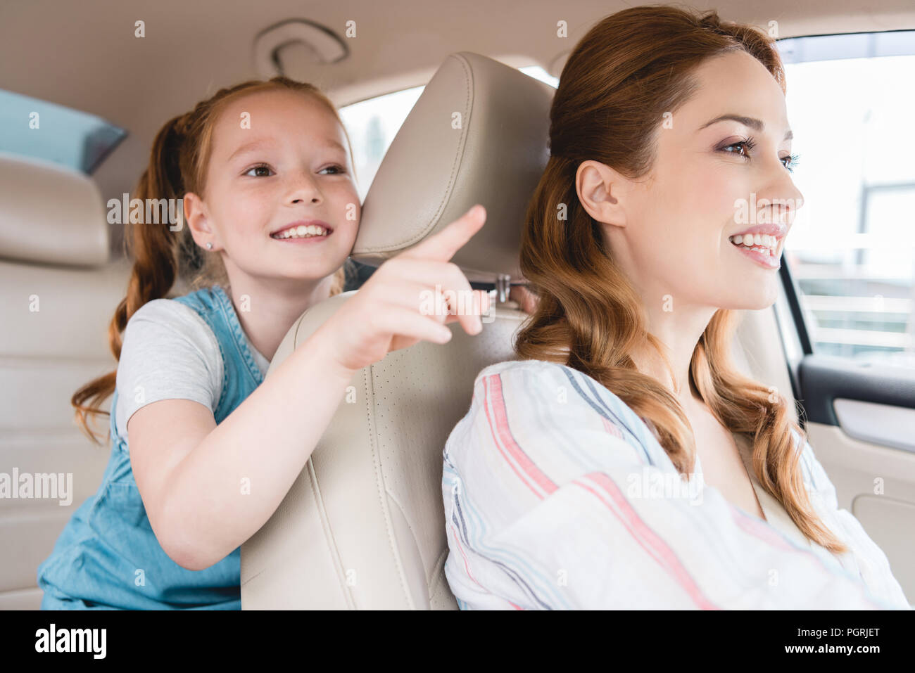 side view of smiling kid pointing away and mother driving car Stock ...