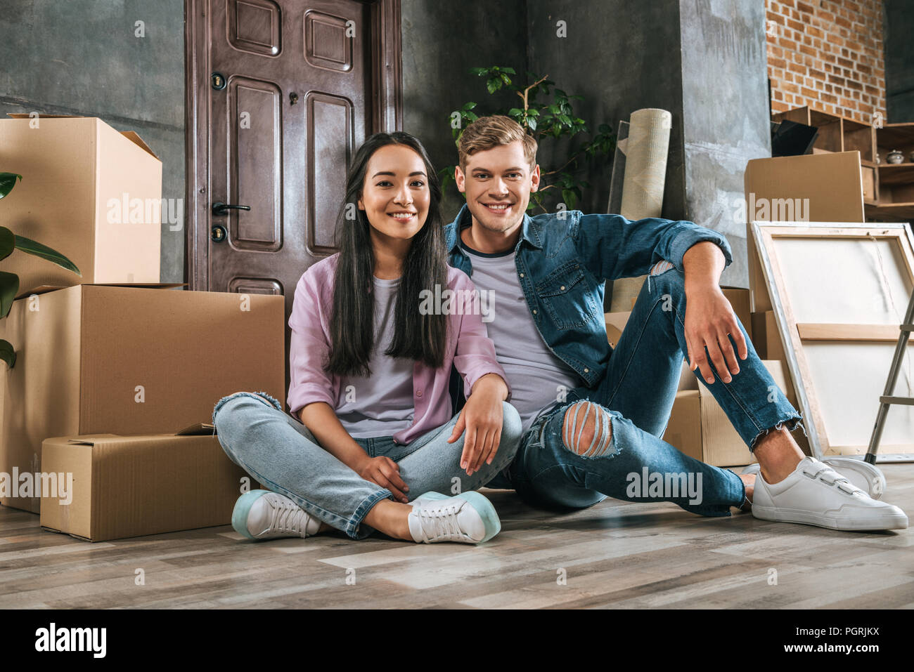 attractive young couple sitting on floor together while moving into new ...