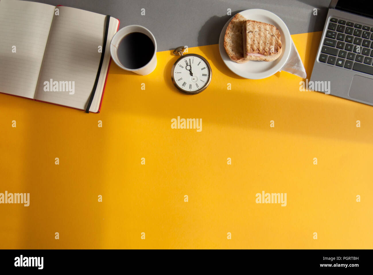 Business accessories including laptop, clock with grilled sandwich view ...