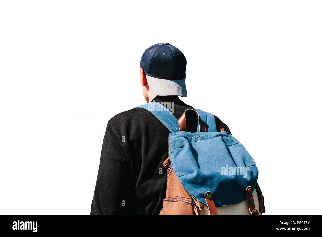 A guy or teenager in a baseball cap with a backpack back view is ...