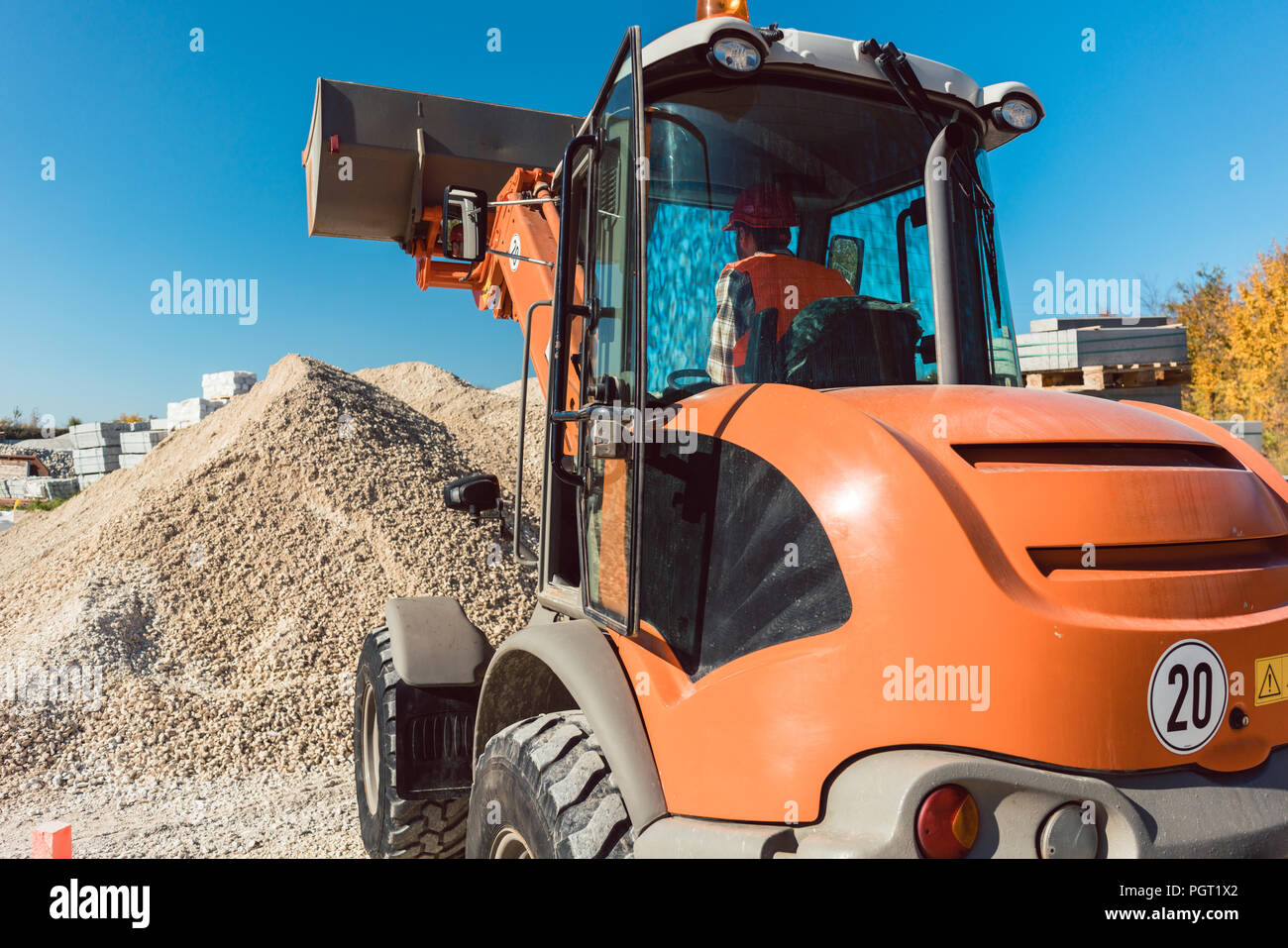 Worker on construction site operating wheel loader Stock Photo - Alamy
