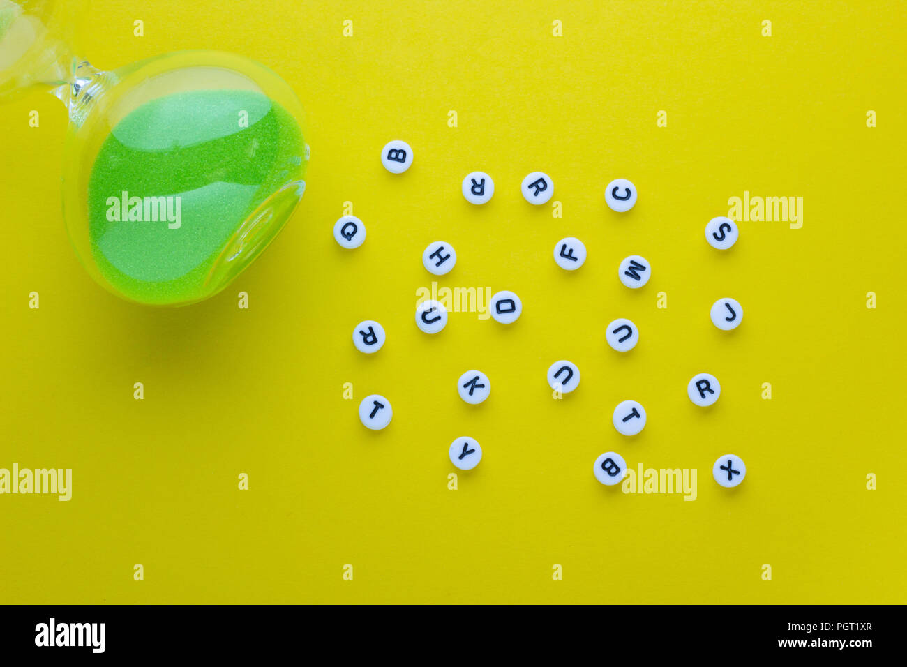 Hourglass with small letters on a yellow background Stock Photo - Alamy