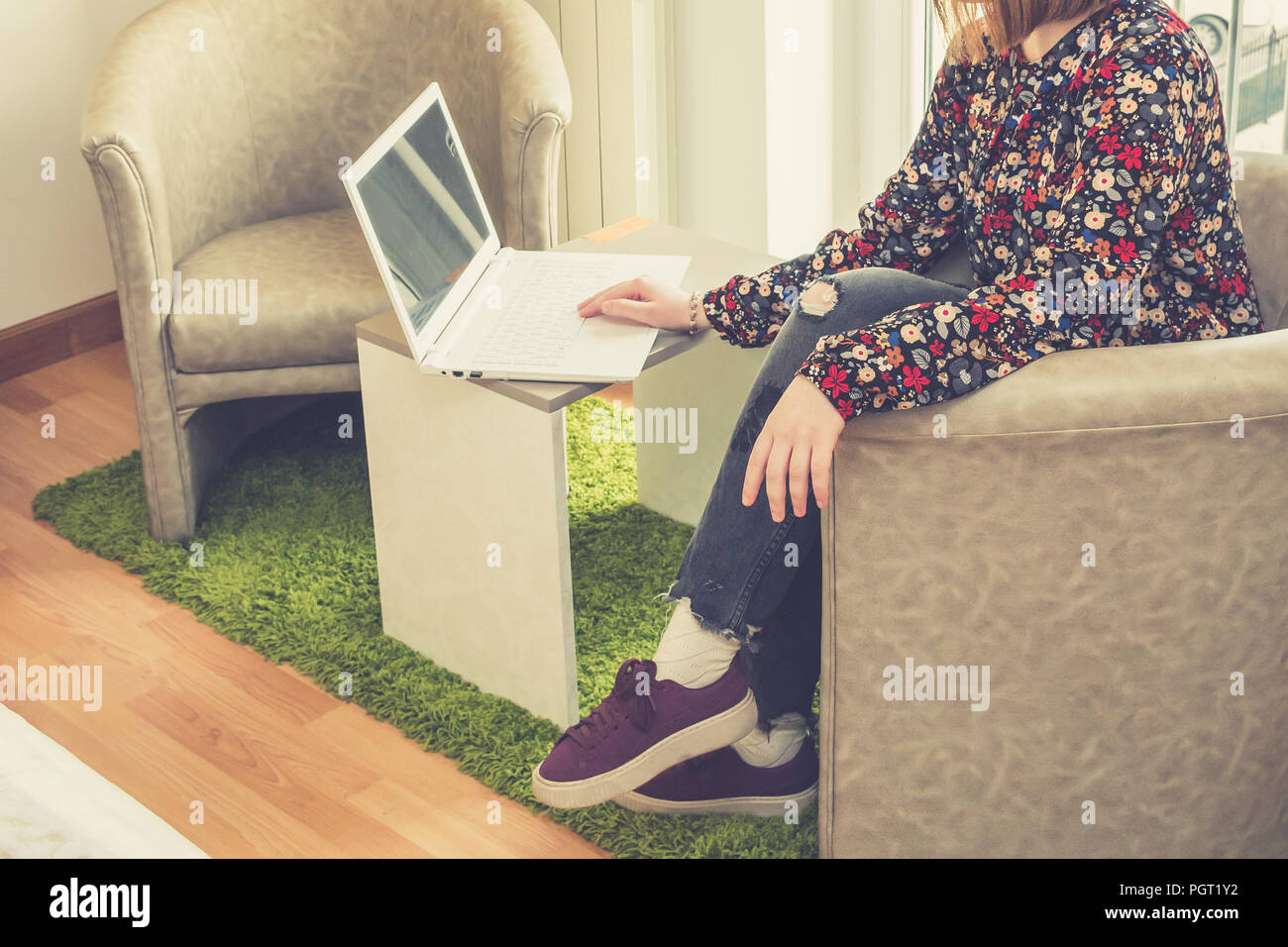 Female sitting in armchair and typing on white keyboard. Woman working ...