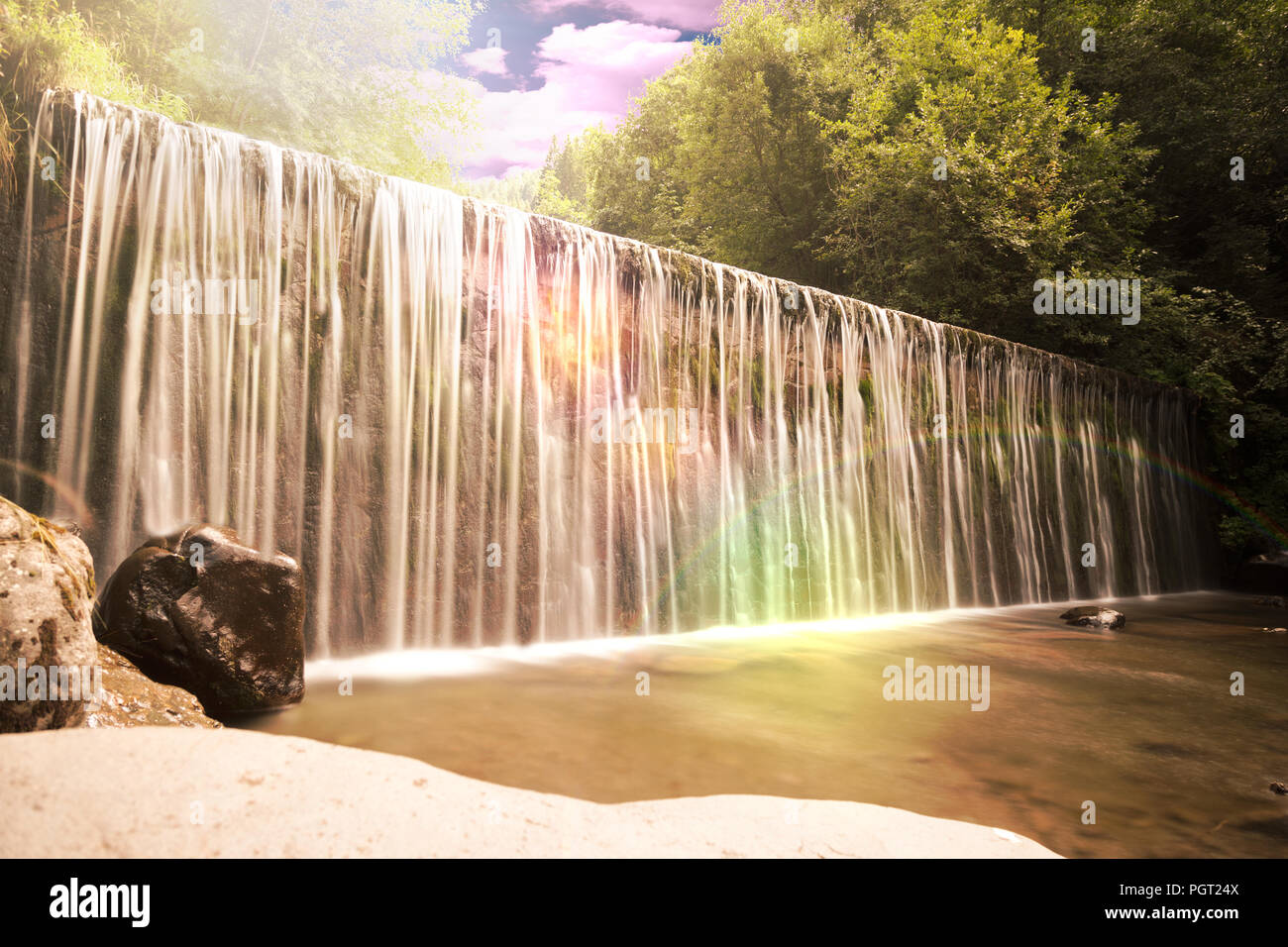 Water flowing over a ledge or dam wall in a picturesque cascade or ...