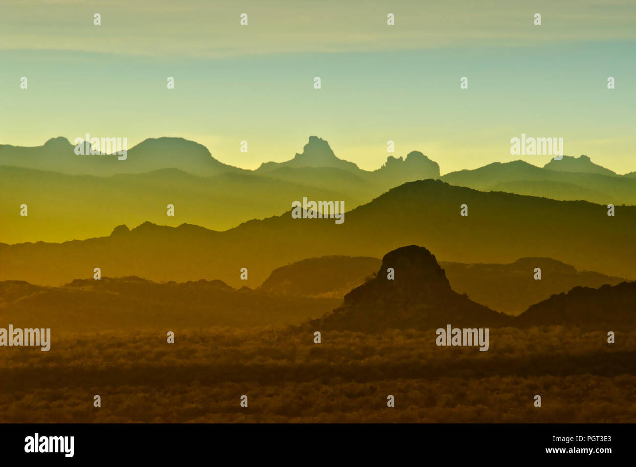 Blue, yellow orange and turquoise sunset over rocky mountains range in ...