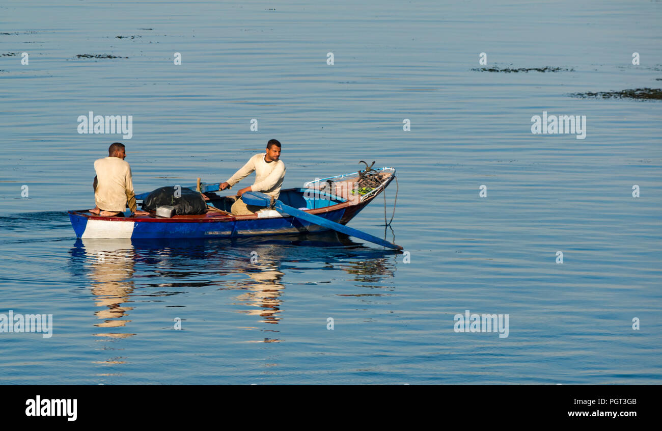 Egyptian local men in rowing boat with oars in early morning light with ...