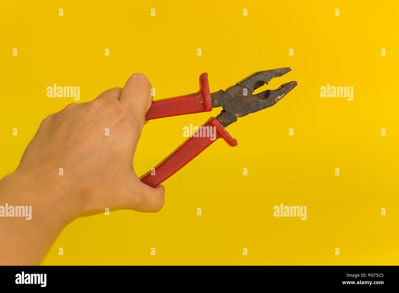 hand holding red pliers on yellow background Stock Photo - Alamy