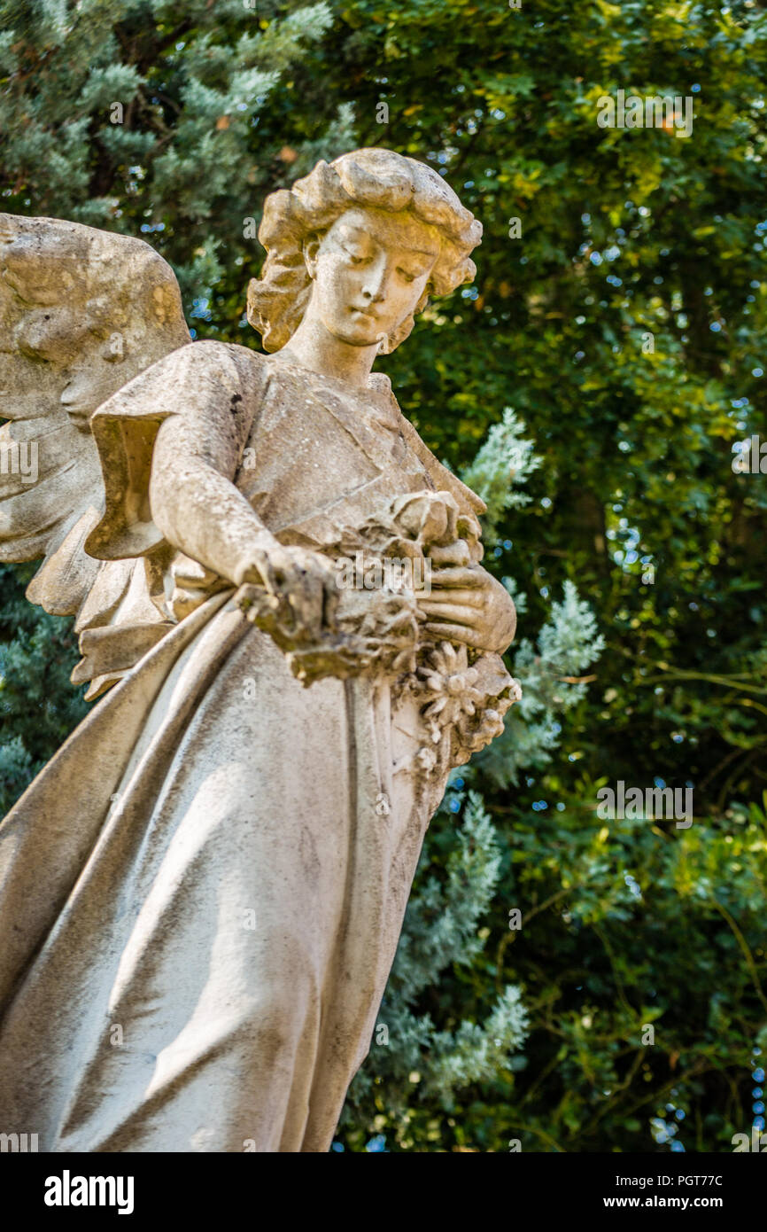 closeup of statue of angel spreading arms and offering flowers Stock ...