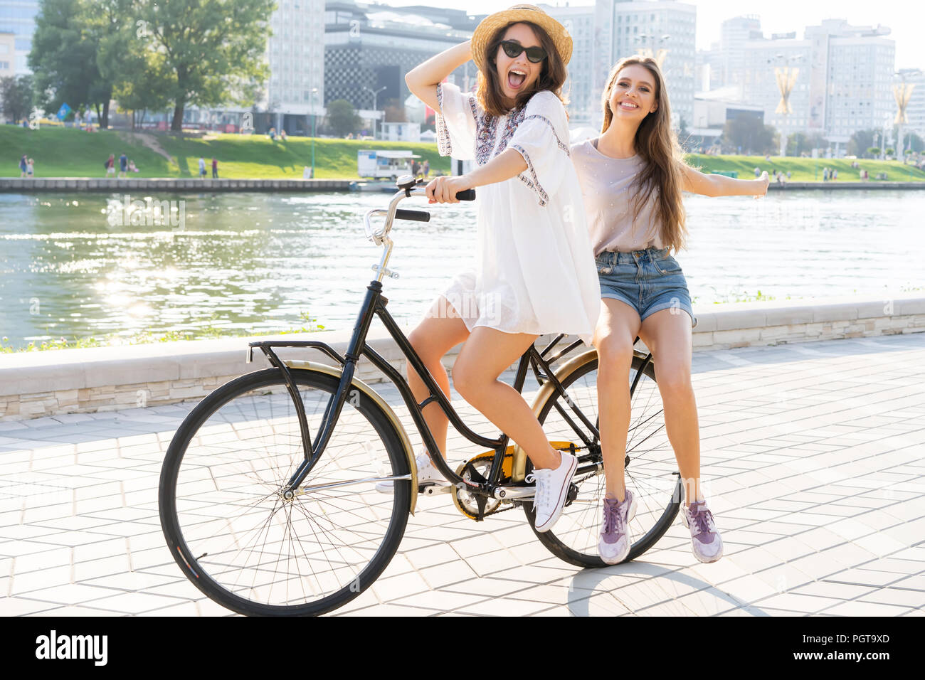 Joyful young women riding a bicycle together. Best friends having fun ...