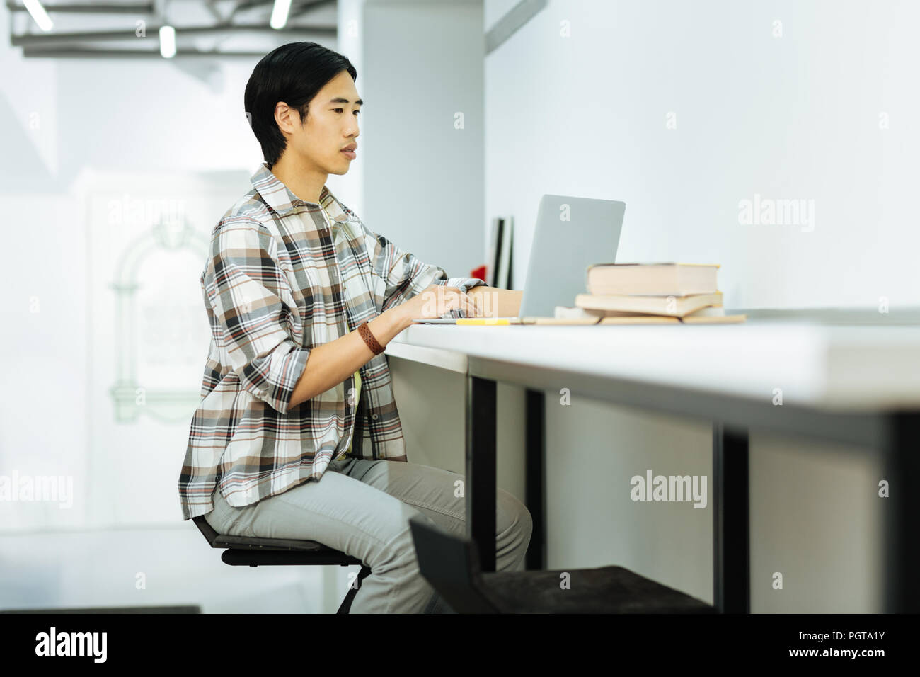 Calm man sitting at the desk and working on his laptop Stock Photo - Alamy