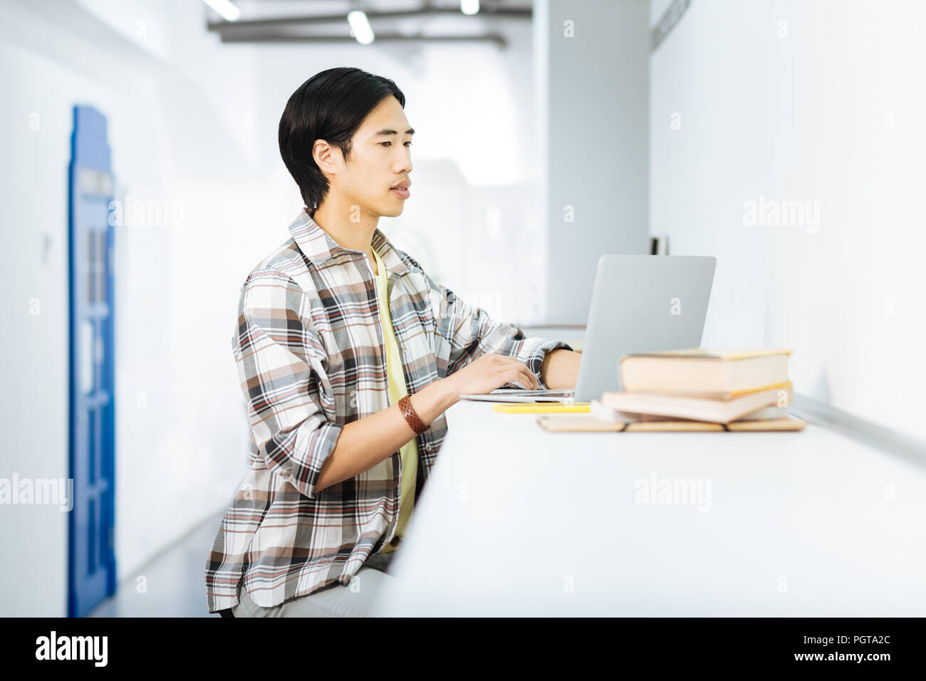 Calm man looking at the screen of a laptop while typing a letter Stock ...