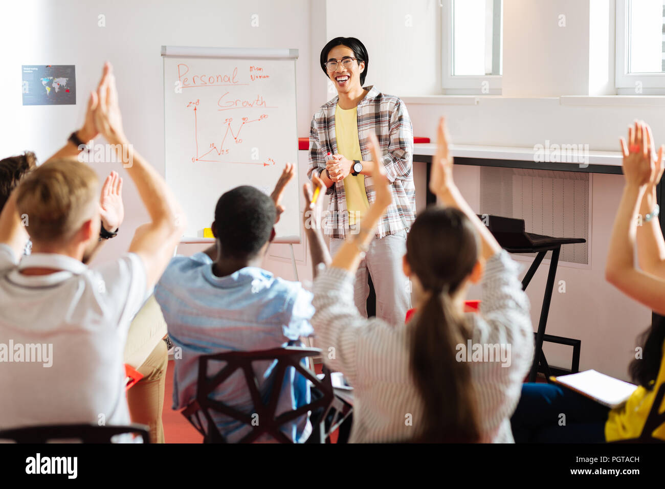 Young speaker feeling satisfied while students raising their hands ...