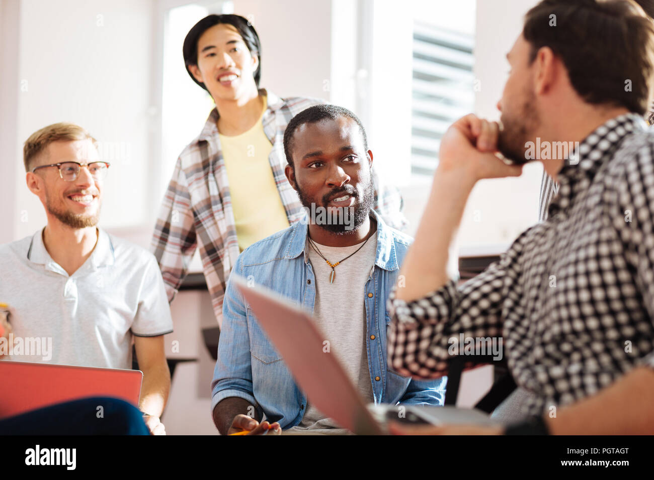 Clever young men enjoying spending time together and looking interested ...
