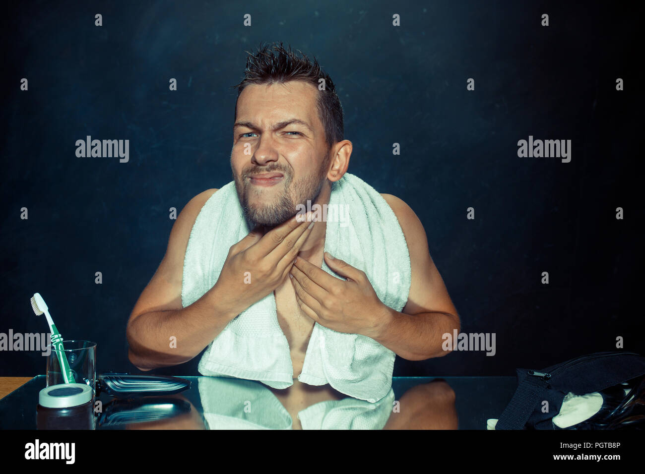 The young man in bedroom sitting in front of the mirror scratching his ...