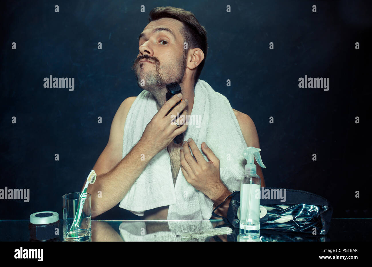 The young man in bedroom sitting in front of the mirror scratching his ...