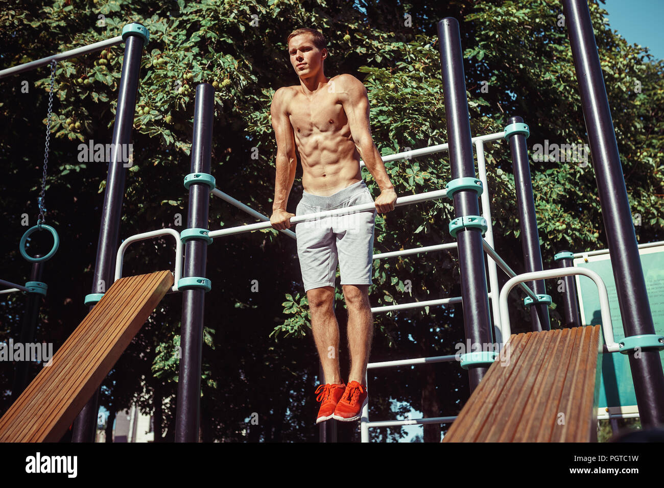 The fit athlete doing exercises at stadium. Caucasian young man outdoor ...