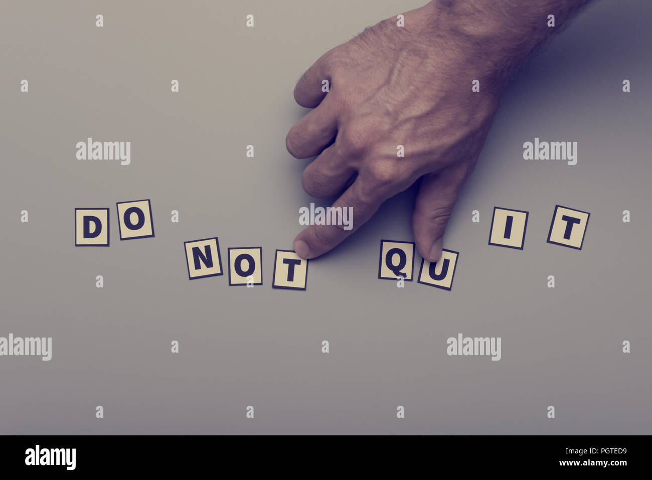 Retro style image of a male hand putting together a Do not quit sign of ...