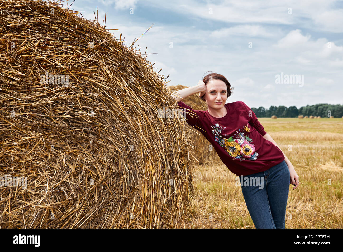 young girl having fun in the field, pushes the haystack Stock Photo - Alamy