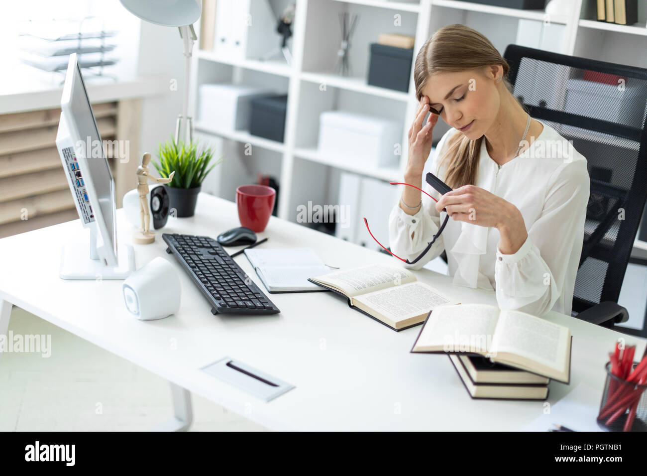 A Young Girl Is Sitting At A Table In The Office Took Off Her Glasses 9703