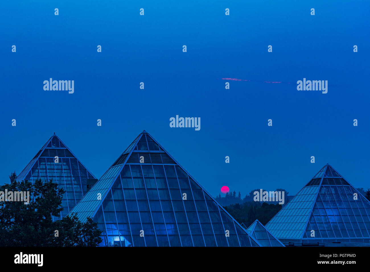 Sun rises through smoke filled sky, Muttart Conservatory Pyramids ...