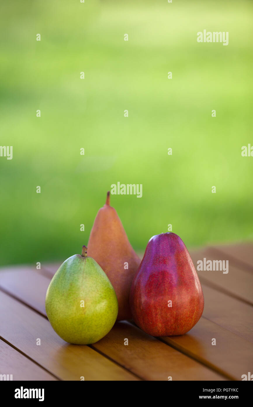 Three different pears on a table with green grass background Stock ...