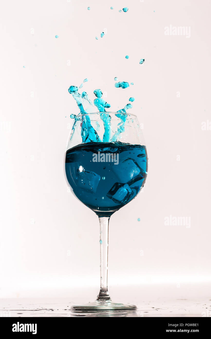 Blue drink splash with ice cubes from transparent glass Stock Photo - Alamy