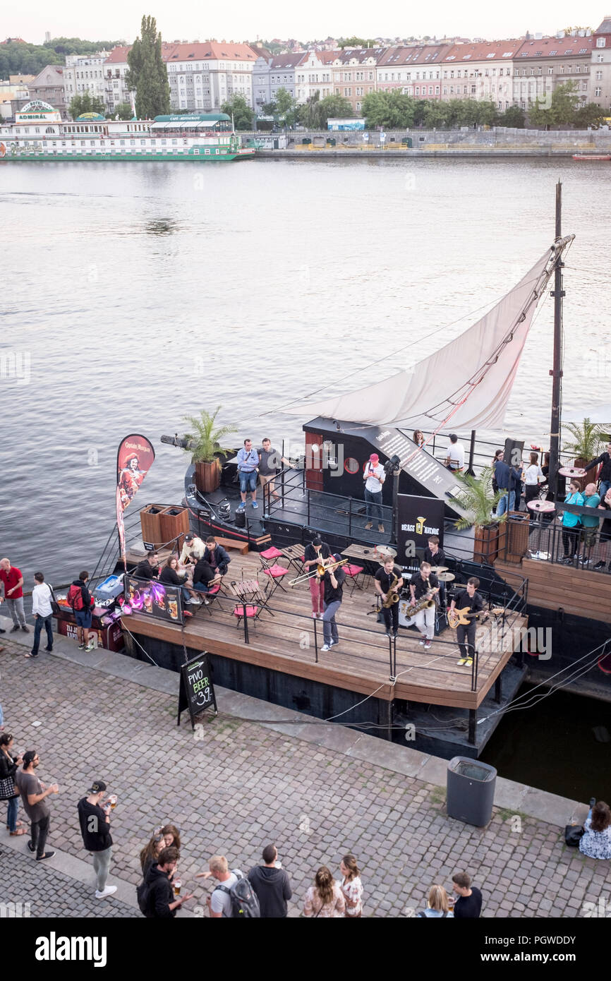 Musicians play on the deck of a barge converted into a bar at sunset on ...