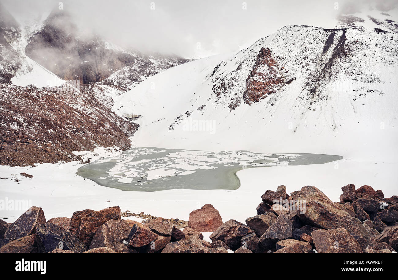 Mountain lake with ice on the snowy mountain Lake of Zaili Alatay in ...