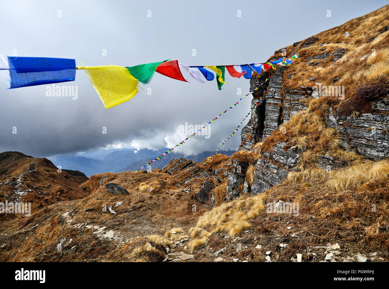 Rocks and Tibetan prayer flags Lung Ta at the Mardi Himal Base Camp at cloudy peaks of Himalaya ...