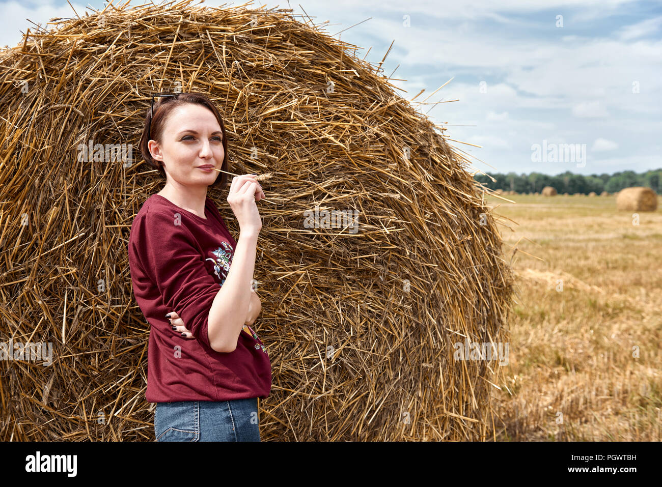 young girl having fun in the field, mowed hay wrapped in a haystack ...