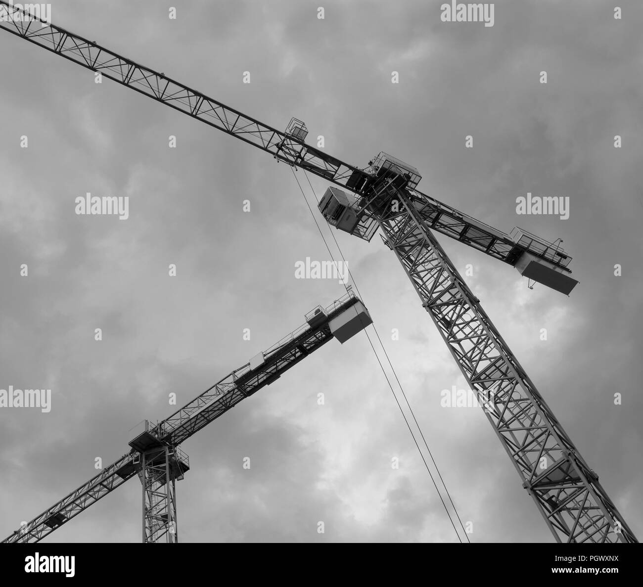 Construction cranes in front of a dramatic sky Stock Photo - Alamy