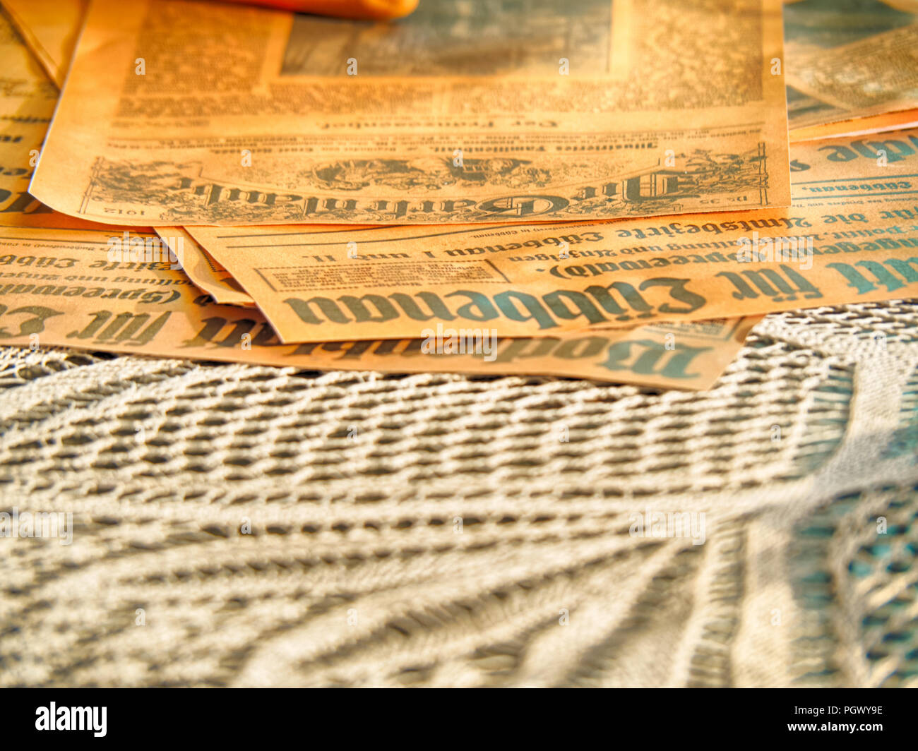 Old German newspapers on an old-fashioned knitted tablecloth, in open ...