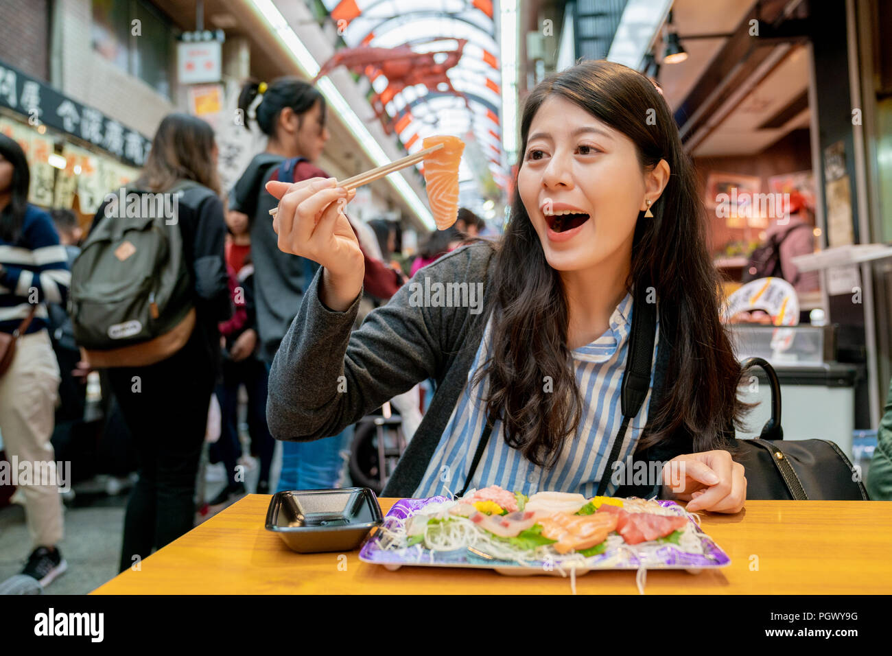 pretty girl picking up sashimi on the table. a traditional market in ...