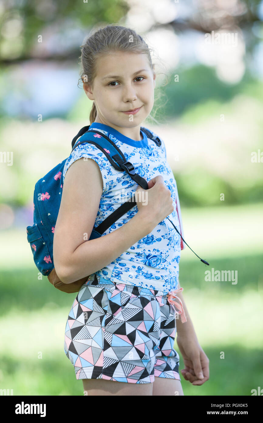 Portrait of ten year old Caucasian girl with small backpack on her back ...