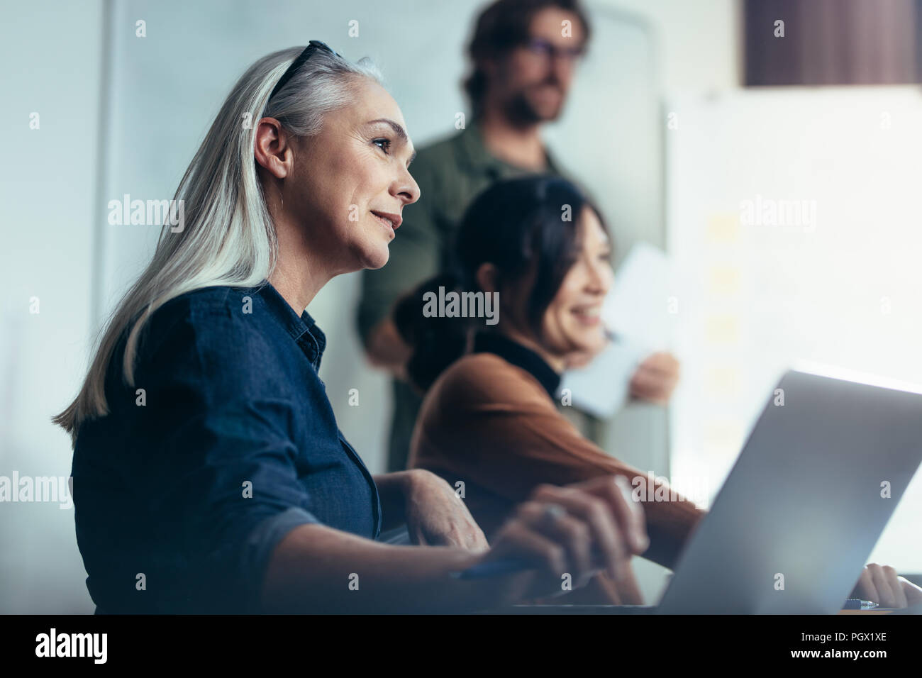 Senior woman with colleagues sitting by during business presentation ...