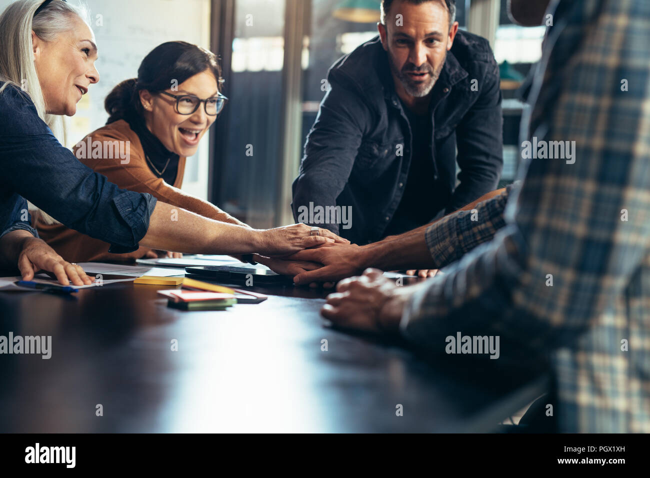 Group of business people stacking their hands over table. Positive ... Group of business people stacking their hands over table. Positive ...