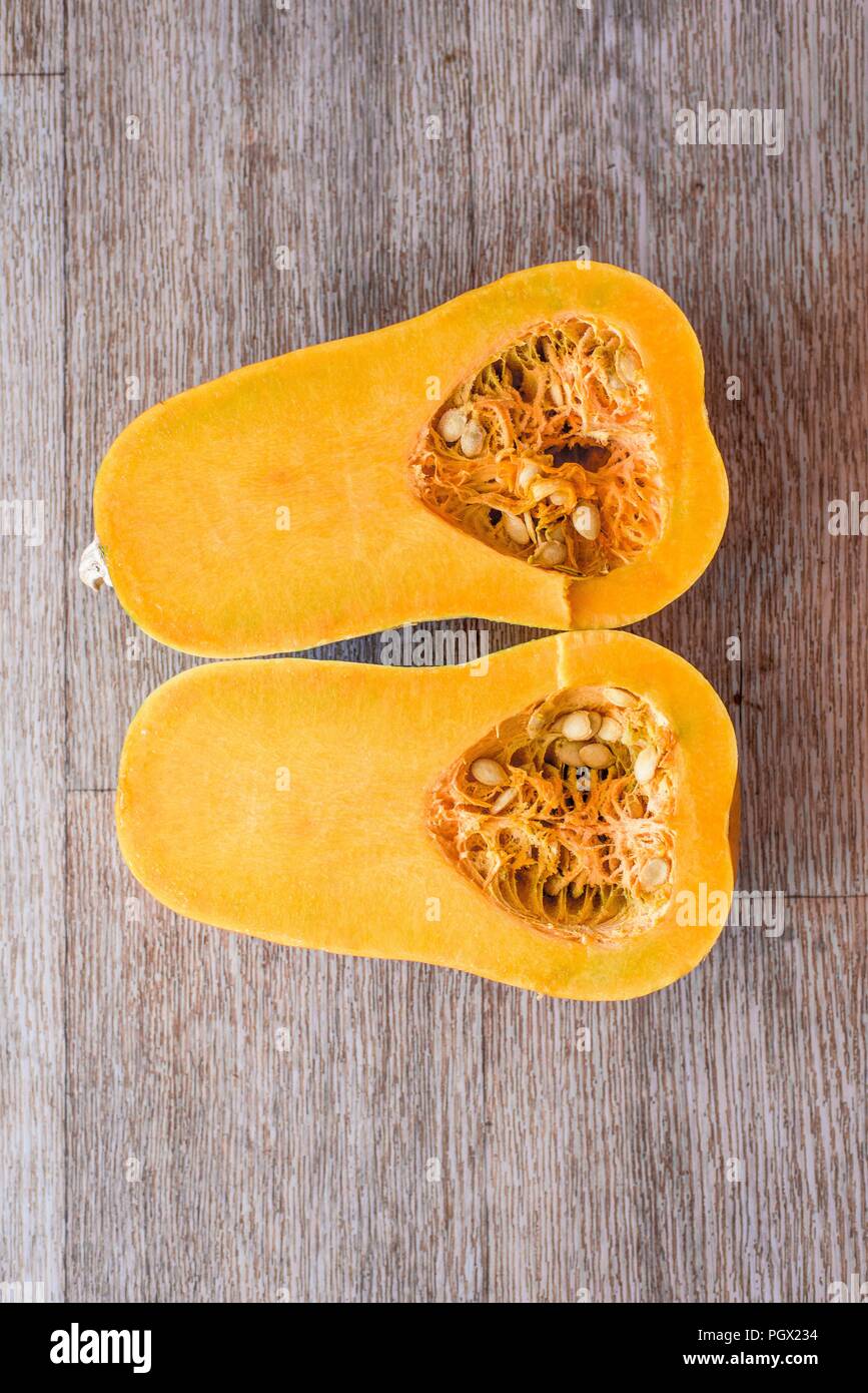 cut pumpkin in half against a wooden texture, close-up Stock Photo - Alamy