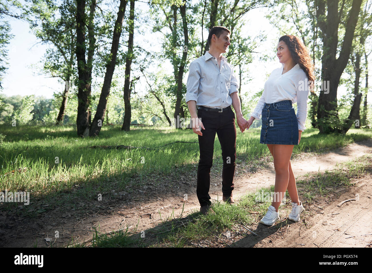 young couple walking in the forest, summer nature, bright sunlight ...