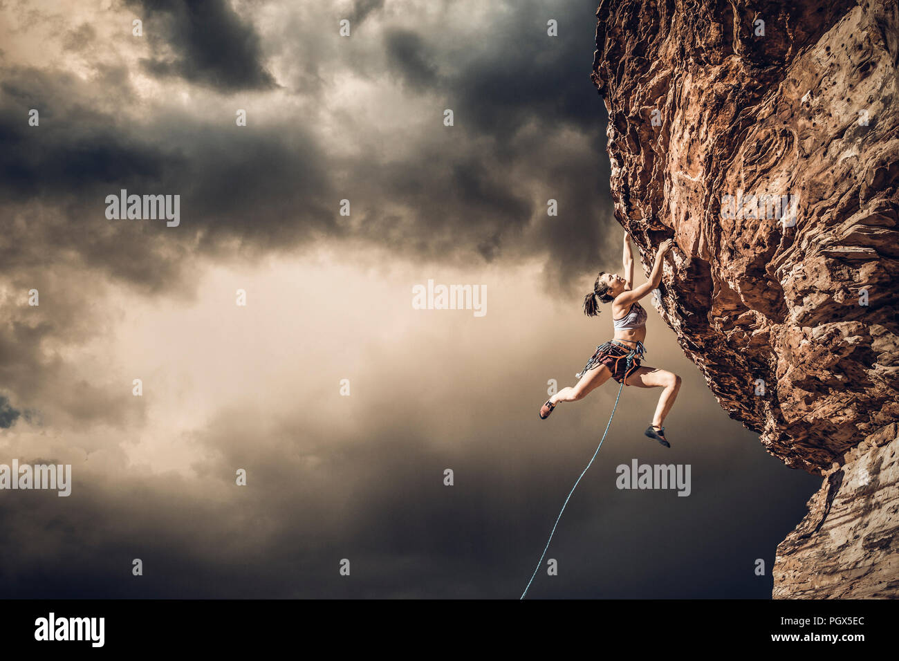 Female climber struggeling up a sheer cliff Stock Photo - Alamy