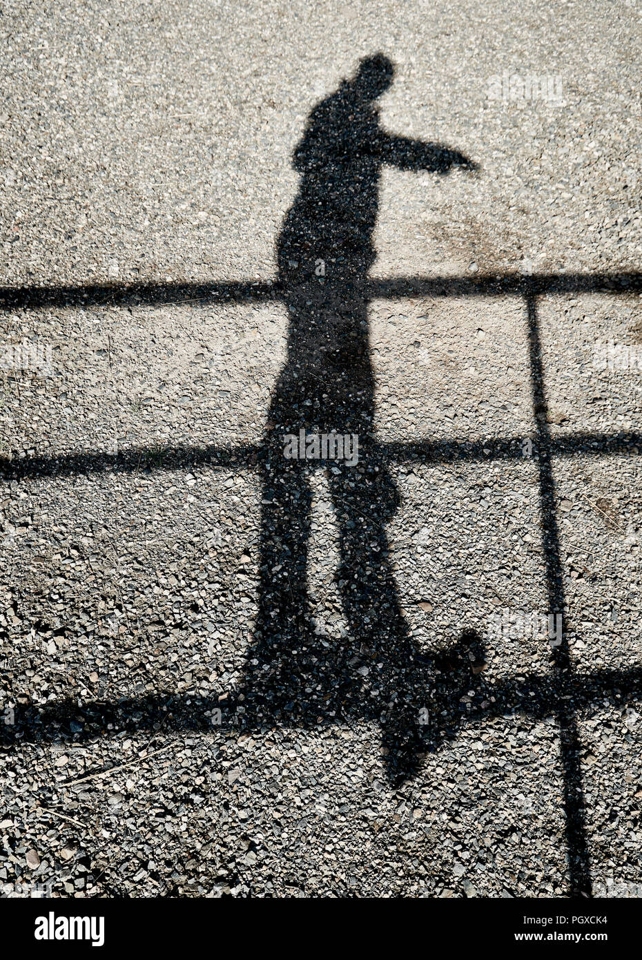 Shadow of a person balancing on one leg on a fence reflected on a ...